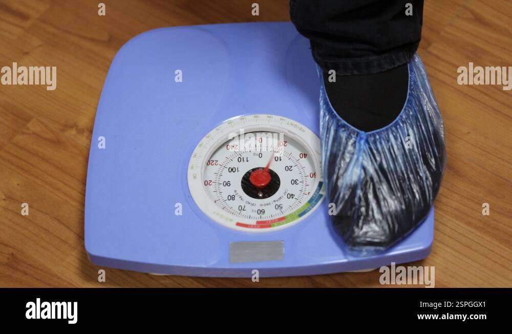 Male feet in shoe covers stepping on blue scales at hospital, close-up ...