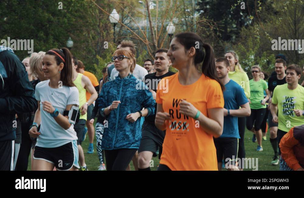 People crowd at city park doing exercises, jogging in one place, summer ...