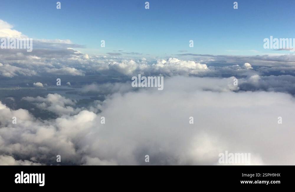 Flight high above land in clouds. On sky view. Aerial flyght in blue ...