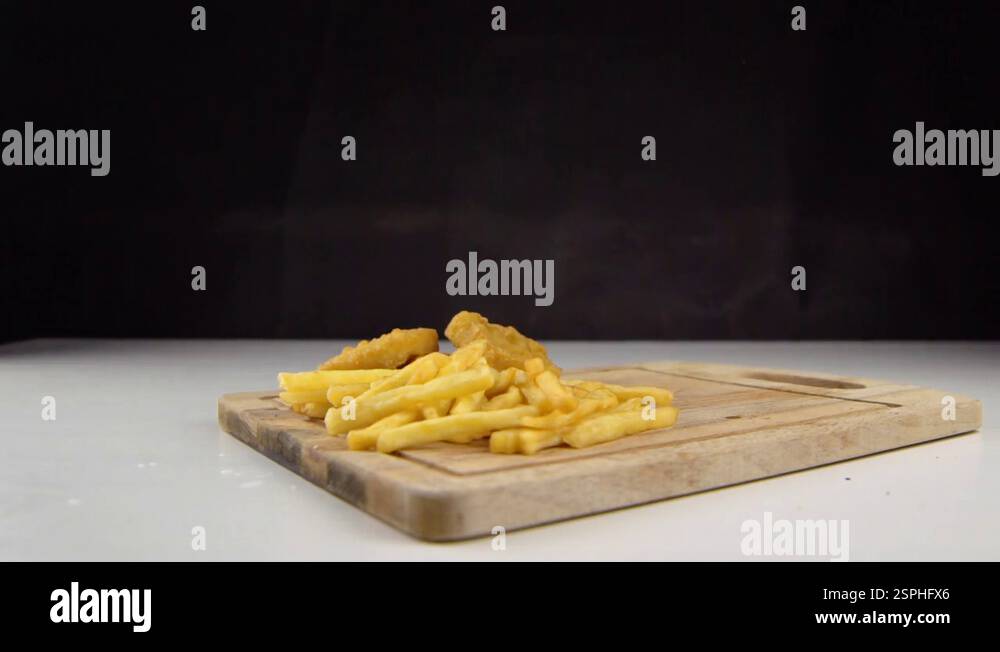 Fried potato chips falling down on hamburger, slow motion, fast food ...
