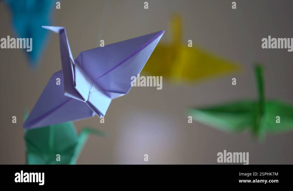 Violet origami crane bird spinning by thread, imagination, relaxing ...