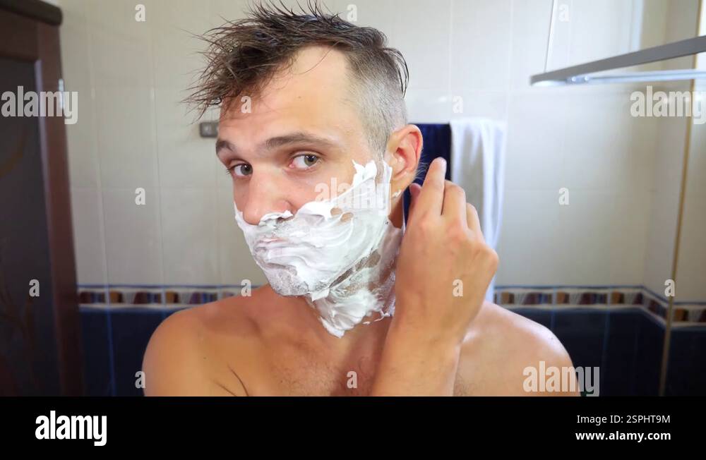 man shaves his face. handsome man shaving in the bathroom. 4k, slow ...