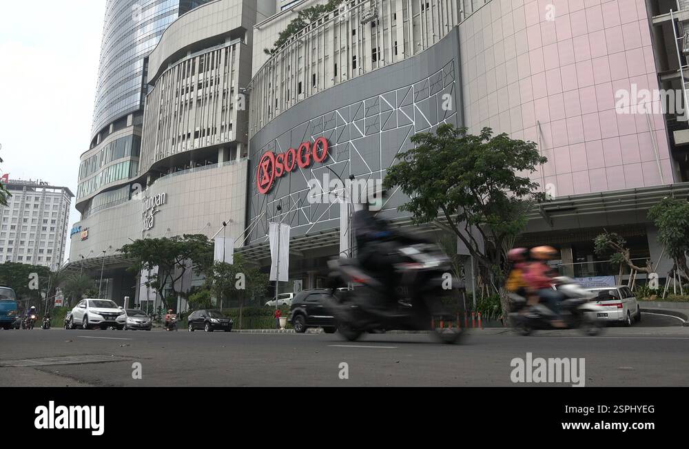 Traffic drives past modern shopping mall in central Surabaya city ...