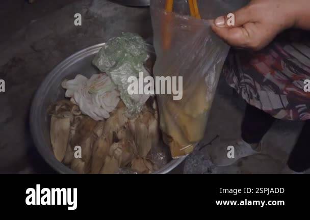 Traditional process of making Mexican tamales with green salsa and red ...