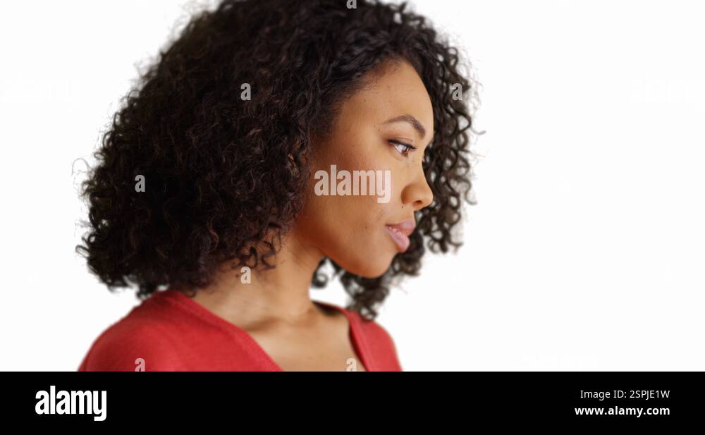 Cute African female with sad expression turns to smile at camera in ...