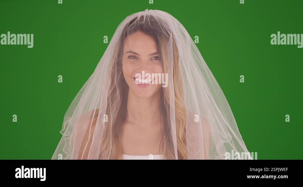 Beautiful bride revealing her face and giggle at the camera on green ...