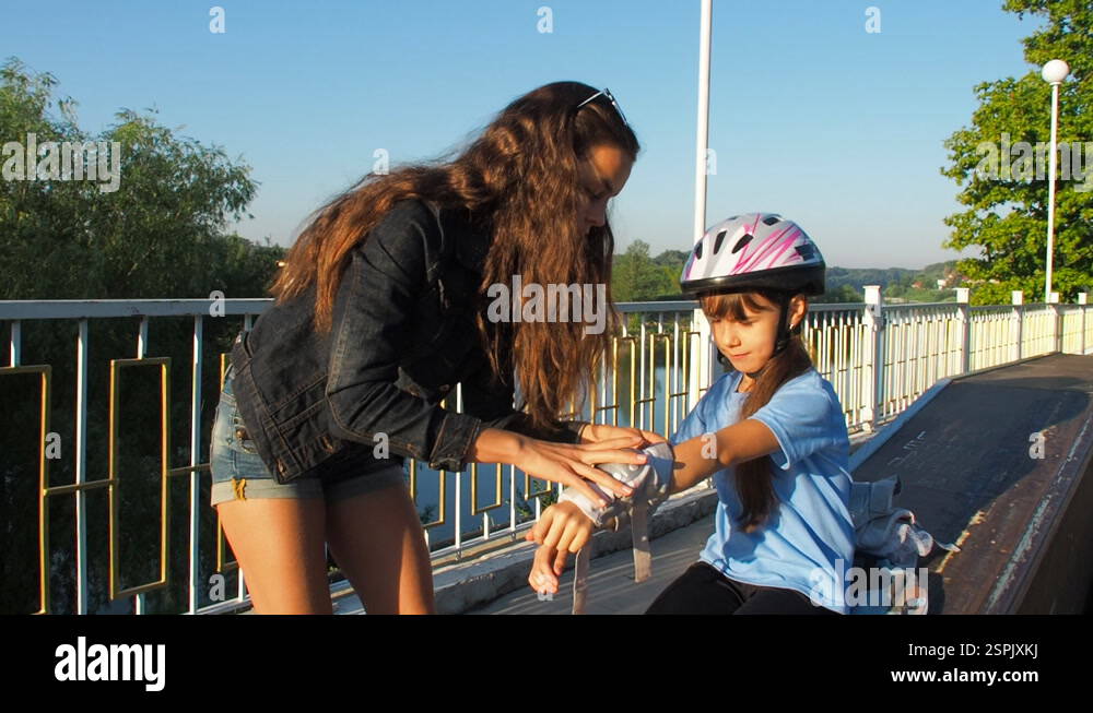 The girl helps the child to wear protection for the rollers Stock Video ...
