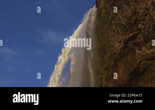 Spectacular waterfall at sunset. Huge flow of water seen from behind ...