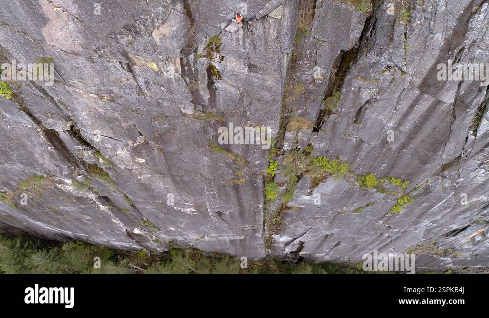 Aerial Reveal of Rock Climber High Up Mountain Cliff with Birds Eye ...
