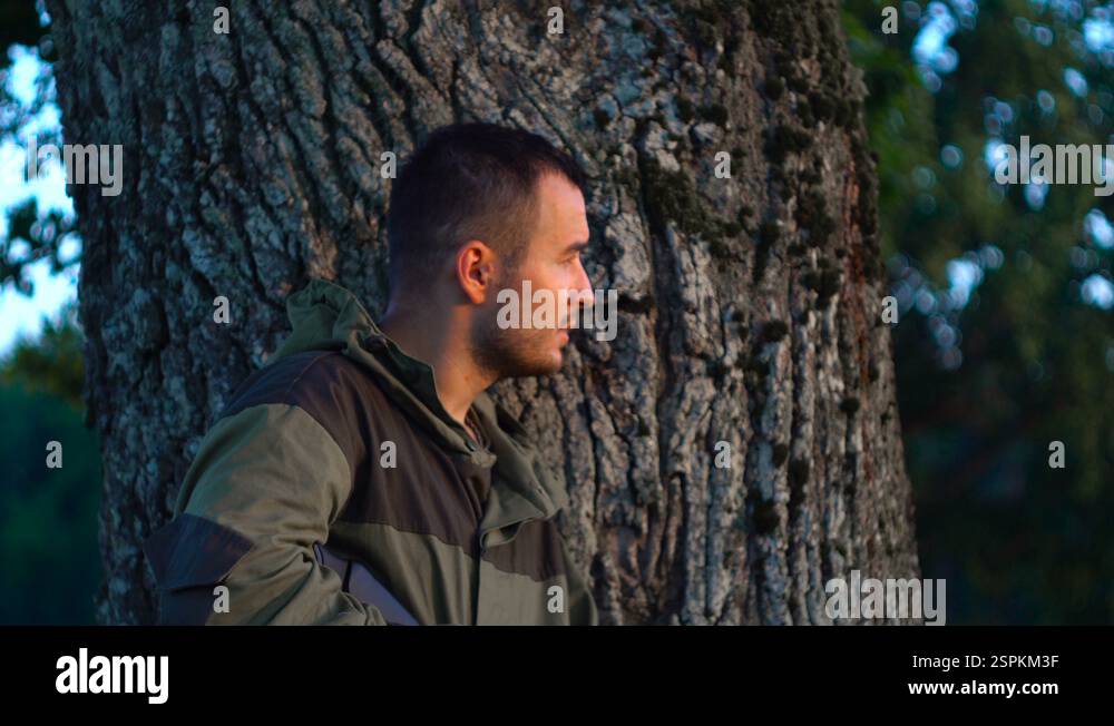 man with a gun on the hunt behind a tree slow Stock Video Footage - Alamy