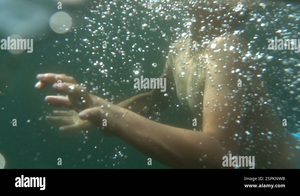 Boy swimming in the pool and resurfaces, slow motion shot at 240fps ...