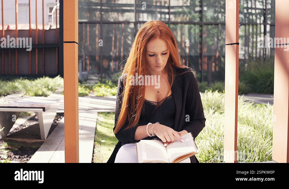 Young woman with red hair reading book in the city Stock Video Footage ...