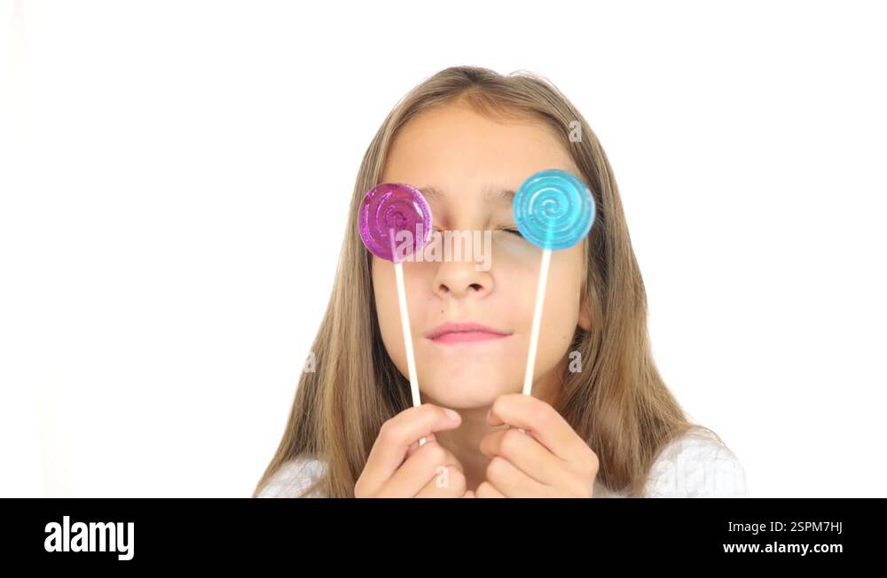 A little girl licks a lollipop stares into the camera and makes funny ...