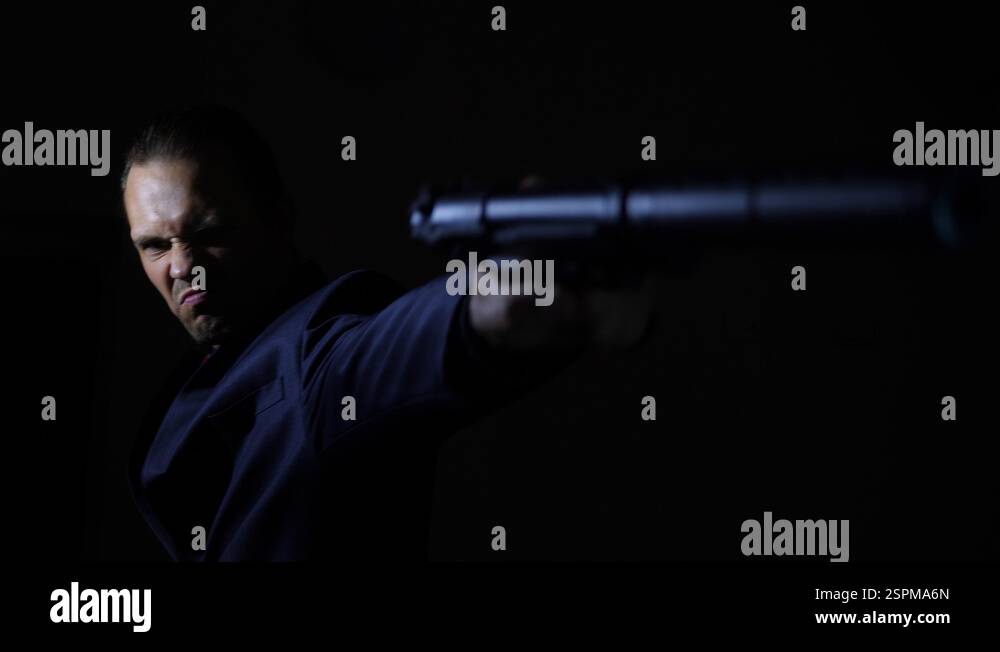 Man pulling out his gun in the darkness and aiming at the camera. 4k ...
