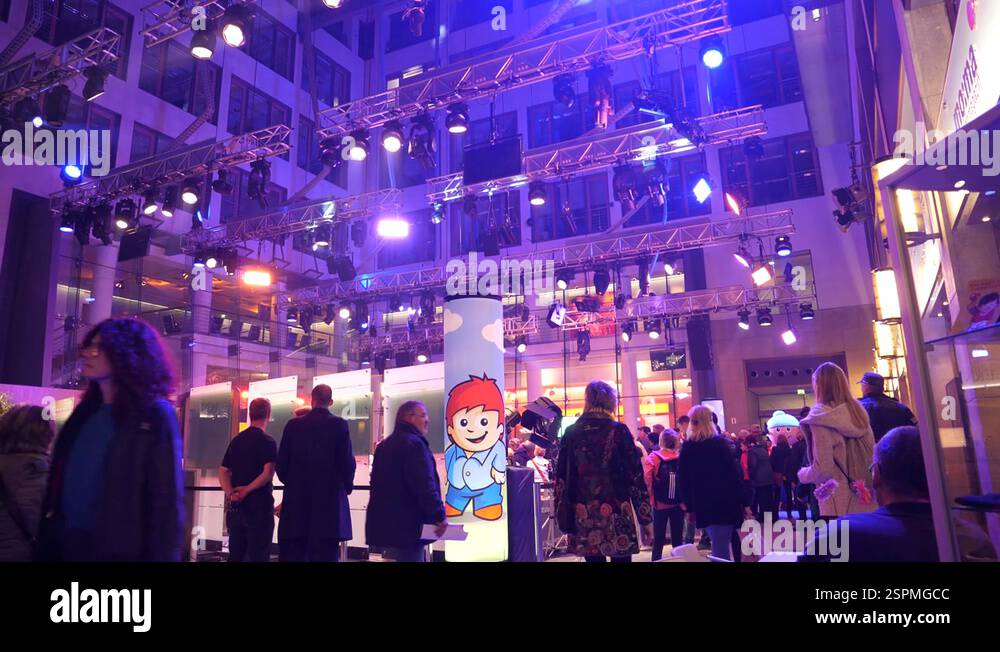 People walk in exhibition hall with suspended stage lighting ...