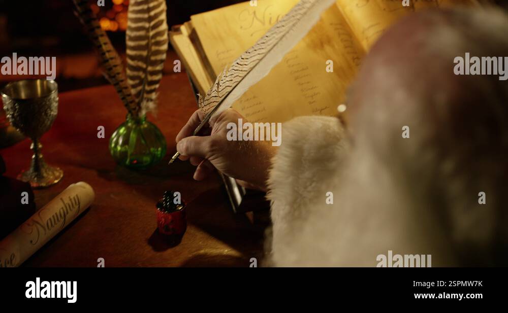 Santa Claus works on his naughty and nice list with a quill pen. Over ...