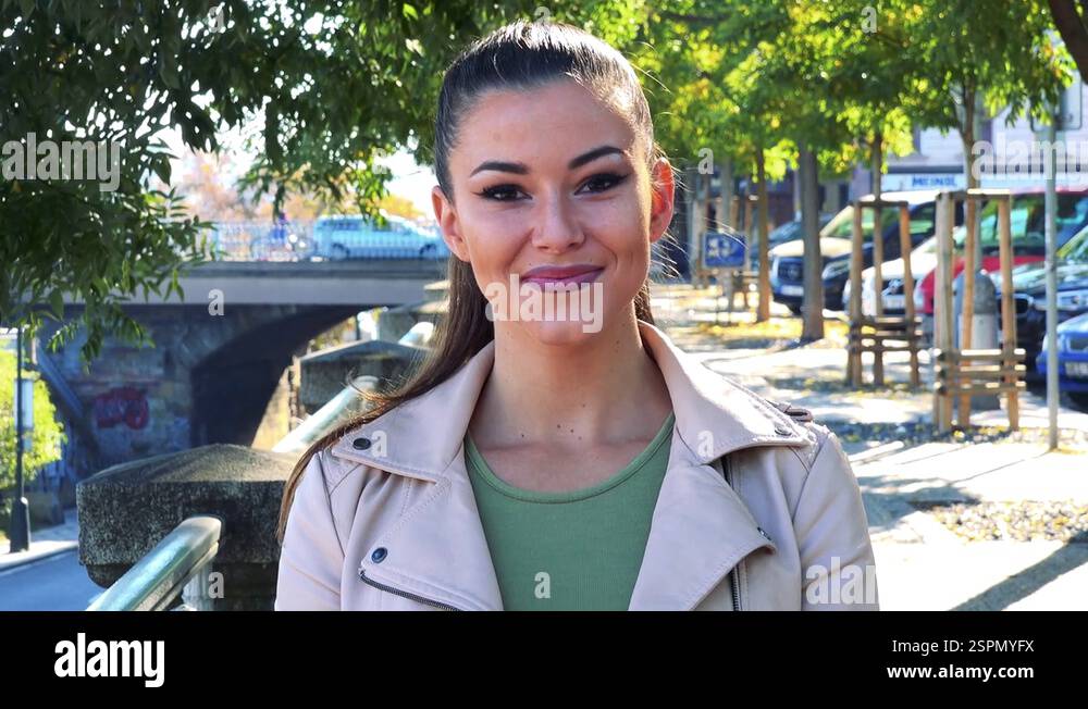Young beautiful woman smiles to camera in the city - street in the ...