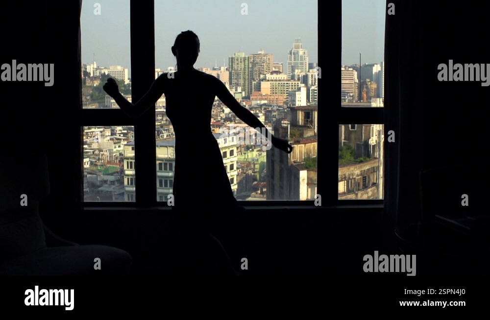 Silhouette of happy woman dancing by window at home, super slow motion ...