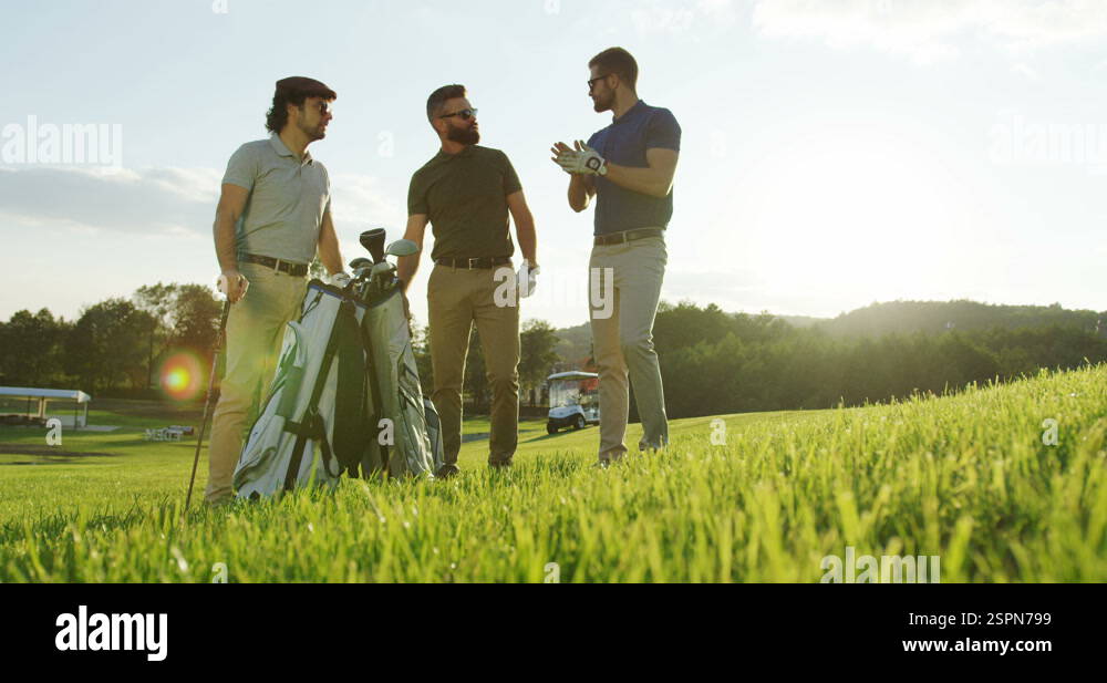 Friends male golf players standing on the golf field, talking near the ...