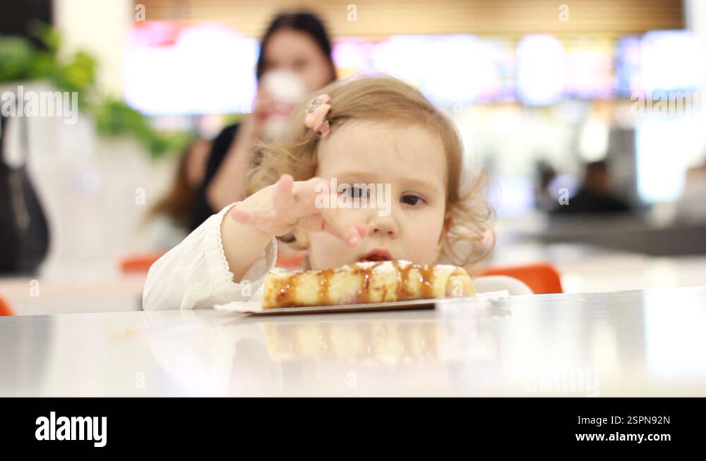 Funny cute child in a cafe eating food - dessert pancakes with sweet ...
