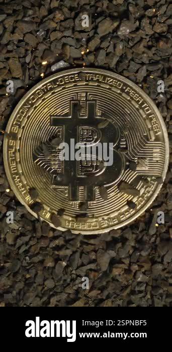 Vertical video. Close-Up of a Gold Bitcoin Partially Covered by Gravel ...