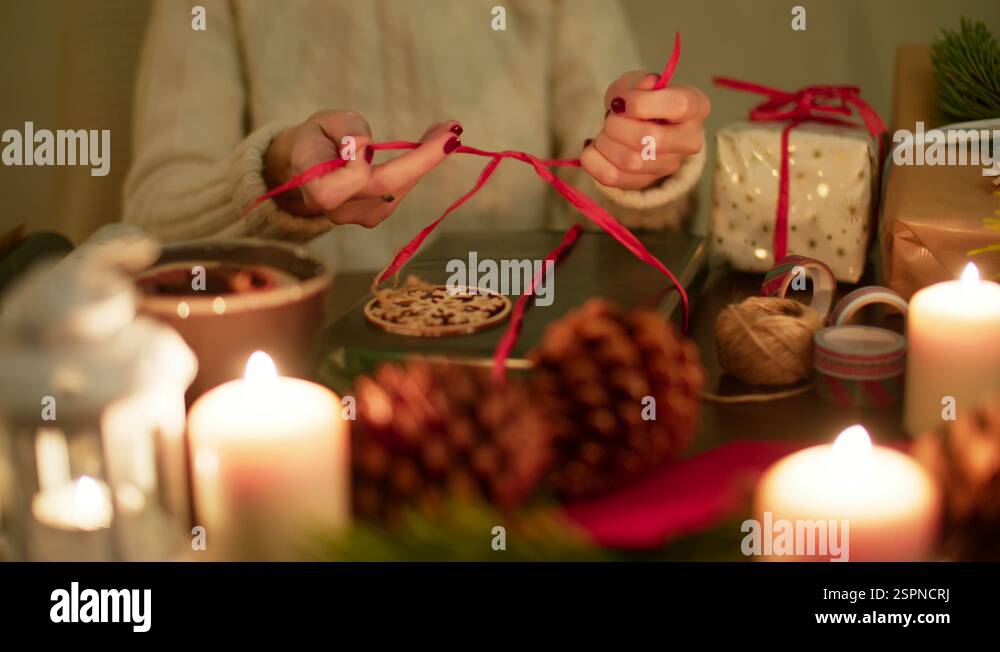 Lady is Wrapping a Christmas Present with Red Ribbon. Warming nice ...