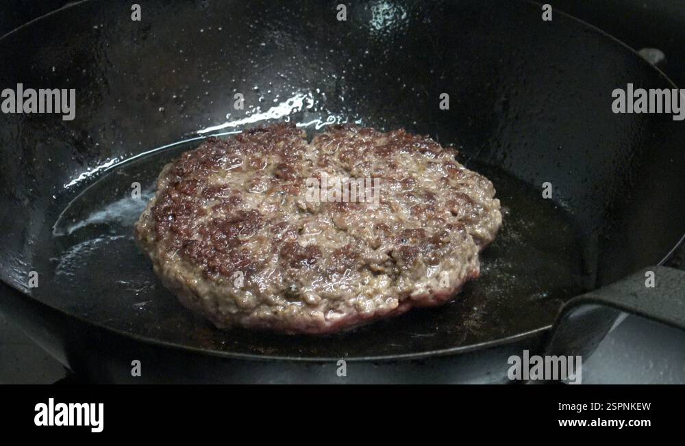 A slab of ground meat on a frying pan is turned over - closeup Stock ...