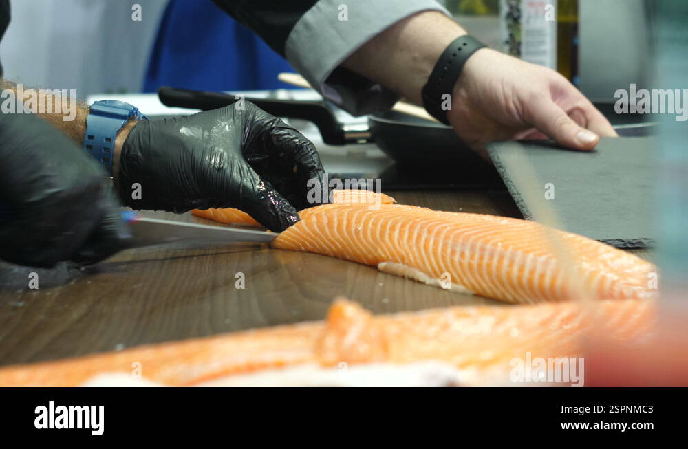 Men's hands in black gloves cut fish fillets into small pieces Stock ...