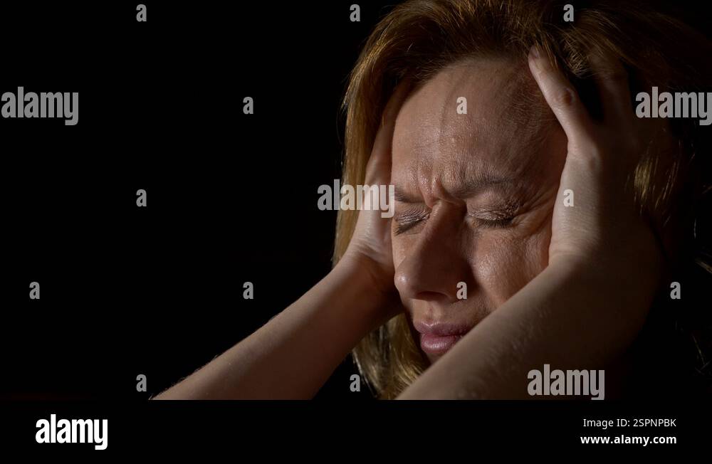 close-up, sad woman with a headache on a dark background. 4k, slow ...