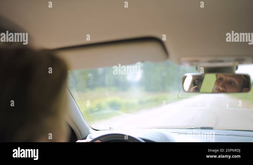Man drives a car on a summer day and his face is visible in the rear ...