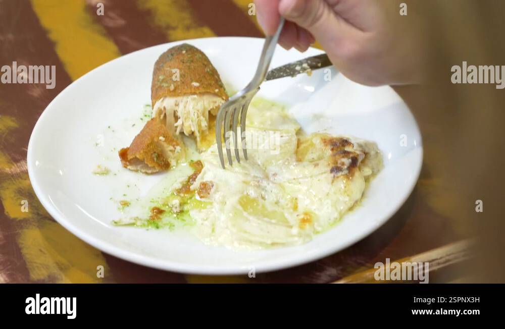 a woman at a restaurant eating a chicken roll with potatoes. 4k Stock ...