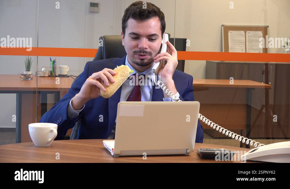 Happy modern worker at office workplace eat lunch sandwich talk on ...