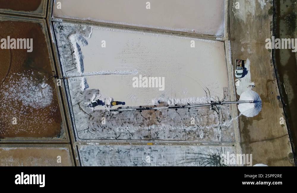 Aerial top-down view showing salt ponds with excavators digging sea ...