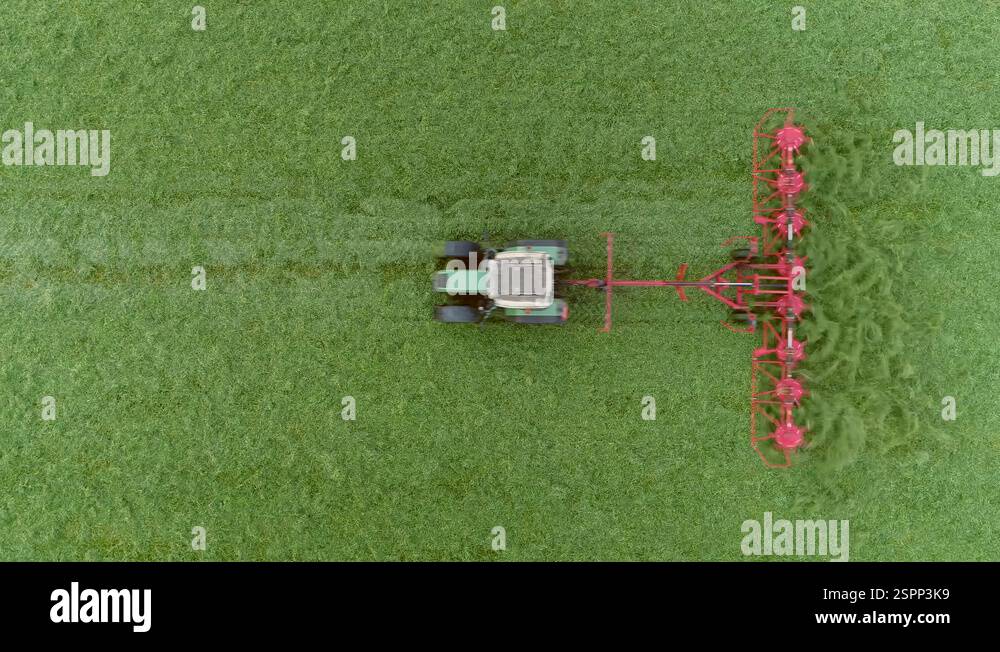 Aerial top-down view of grass land tractor driving over raking grass 4k ...