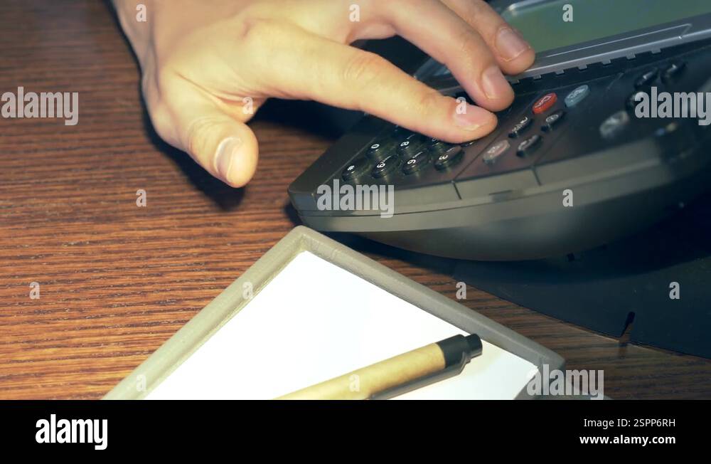 close-up of a male hand pushing a button on a landline phone in a hotel ...