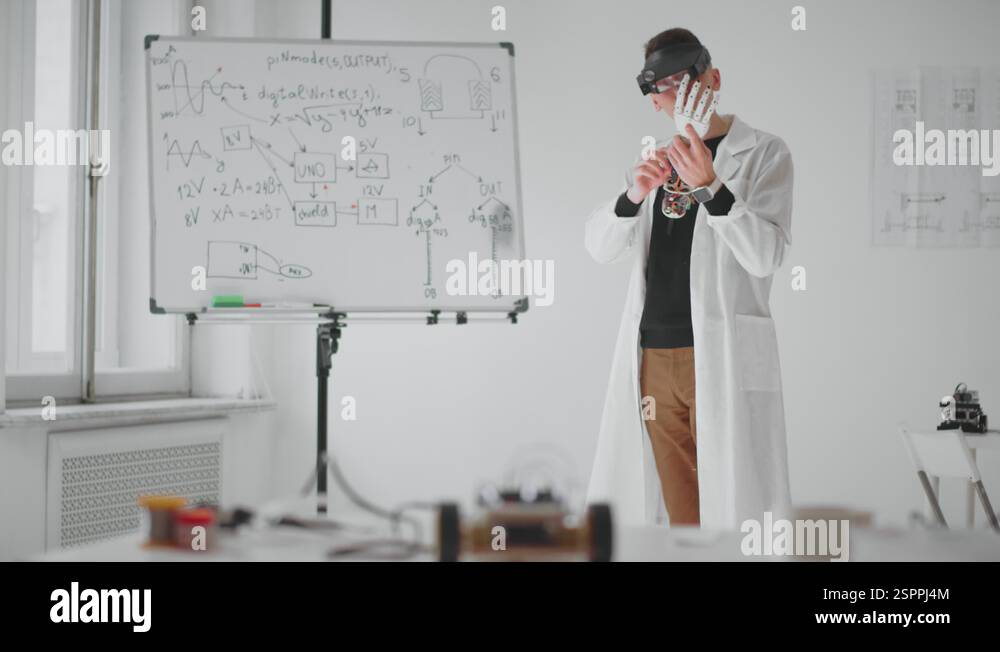 Man inventor looking at robotic arm prosthesis through glasses with ...