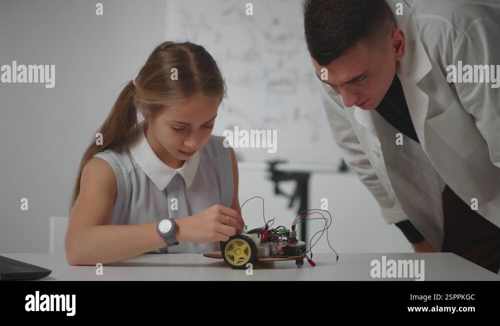 School girl constructing model bot car at table together teacher in classroom Stock Video ...