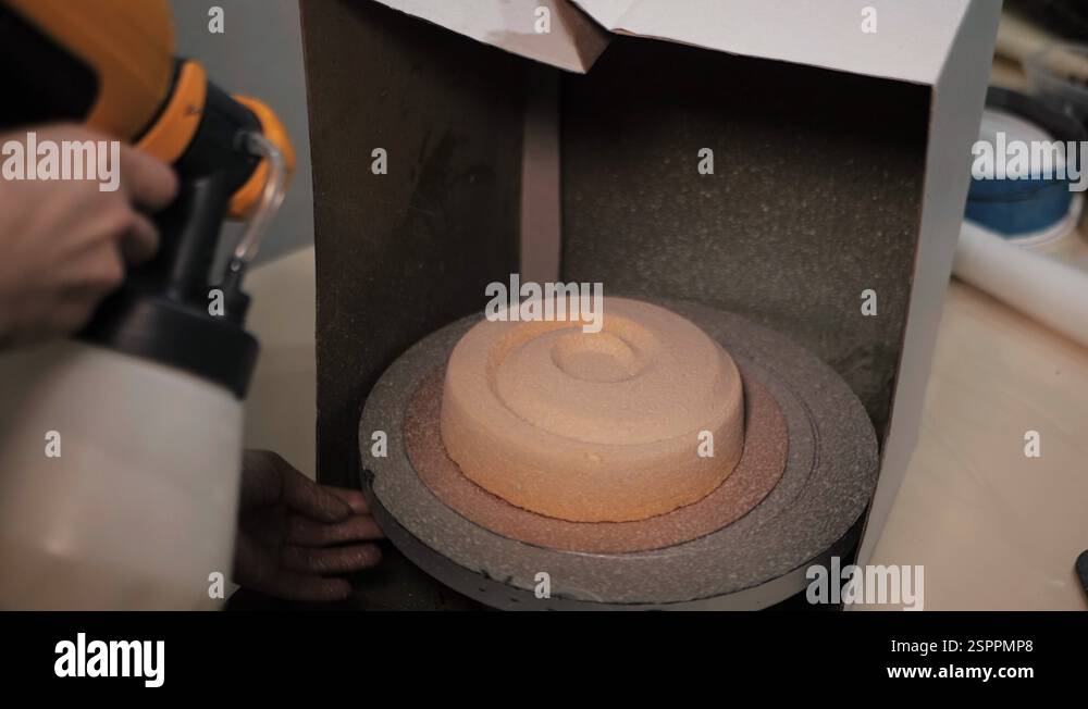 confectioner covers a cake from a spray gun glaze. hands baker decorate ...