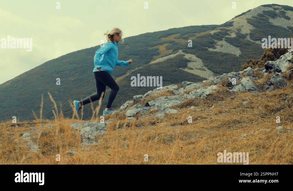 Running woman a run training in mountains background under sky with ...