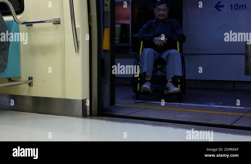 Low angle shot of people pushing wheelchair for old man to take MRT ...