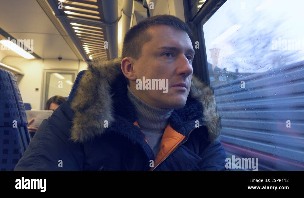 Sad man in a park jacket travels by train, looking out the window Stock ...
