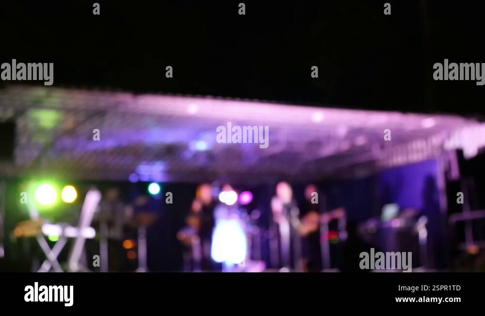 Blurred artists sing on scene in the evening on a local fairground. Out ...