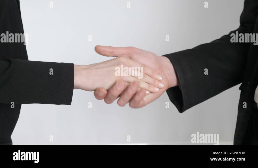 A young man and a girl in suits shake hands. Female and man hands ...