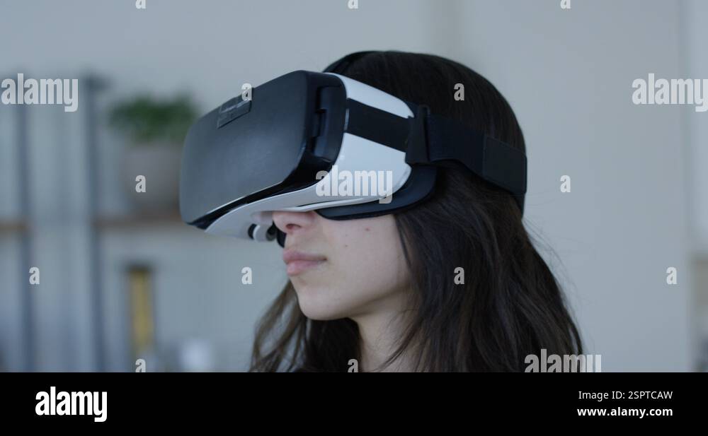 Young hip woman wearing VR 360 goggles in living room - moving head ...