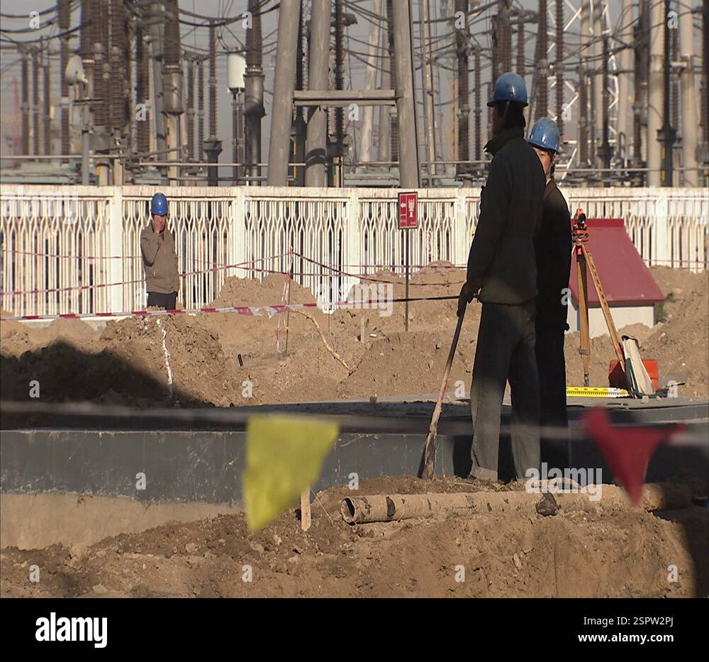 Work crew digging a ditch on the grounds of Shenhua Sanhe power plant ...