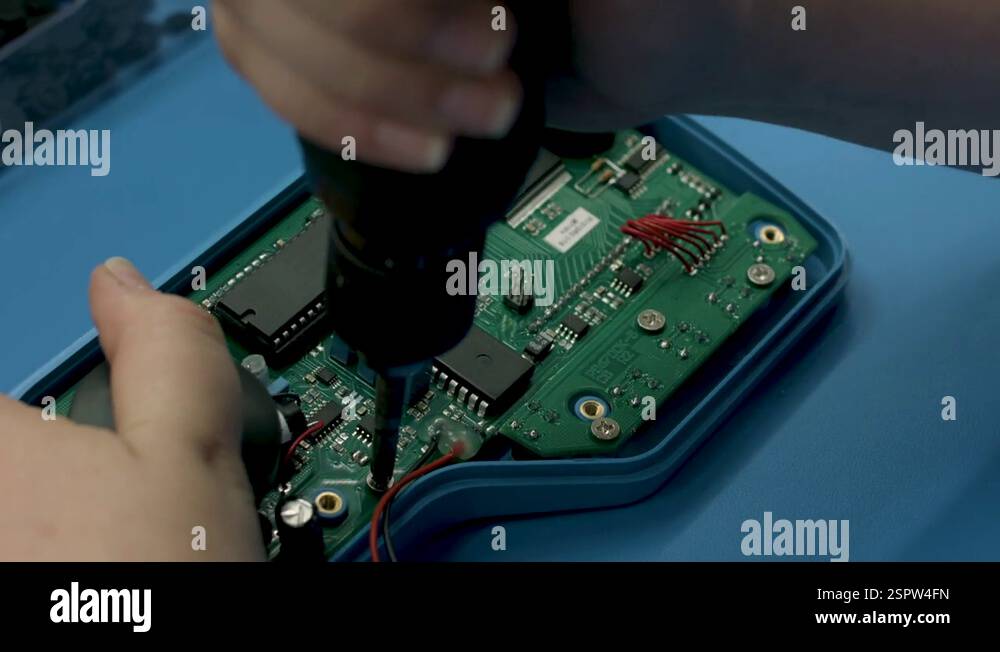 Industrial setup. Factory worker soldering components on a printed ...