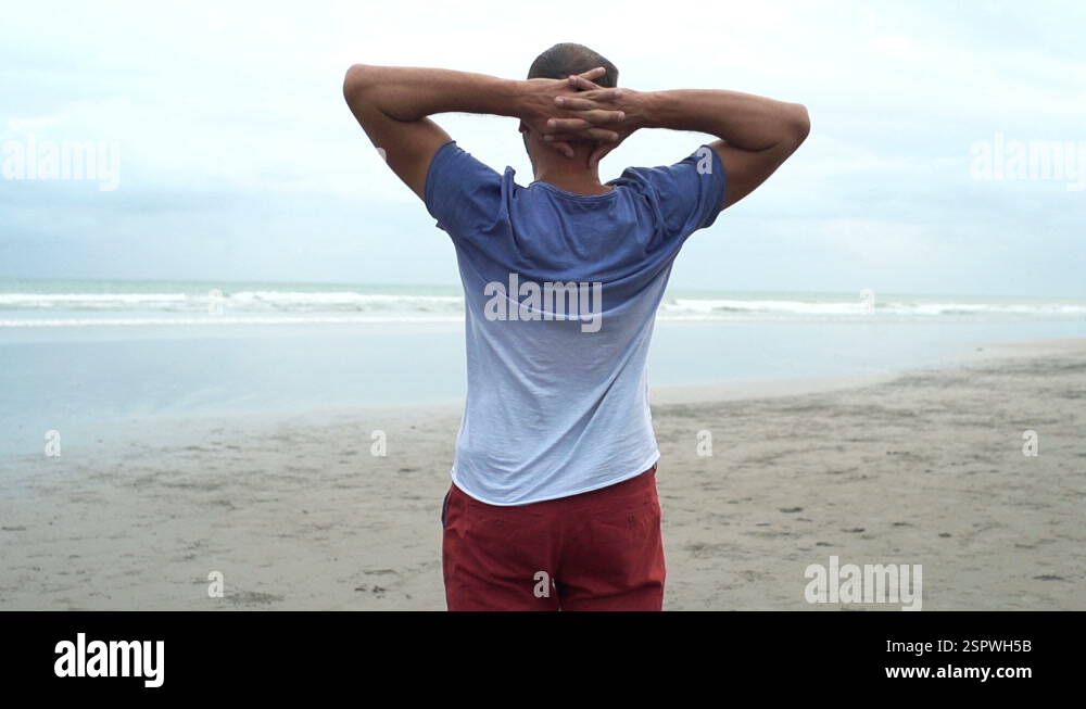 Young man stretching arms and enjoying day on beach, super slow motion ...