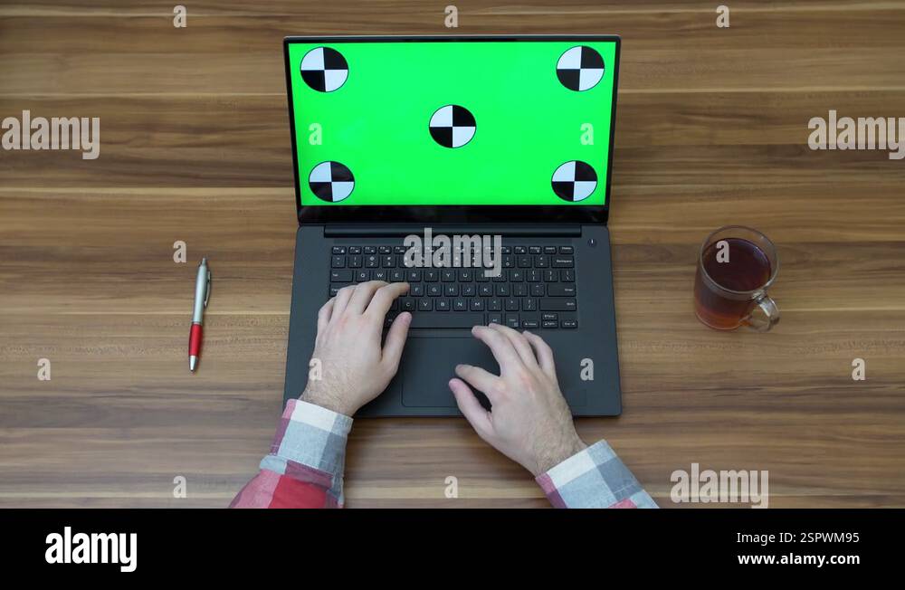 Office table with laptop computer with green screen and male hands ...