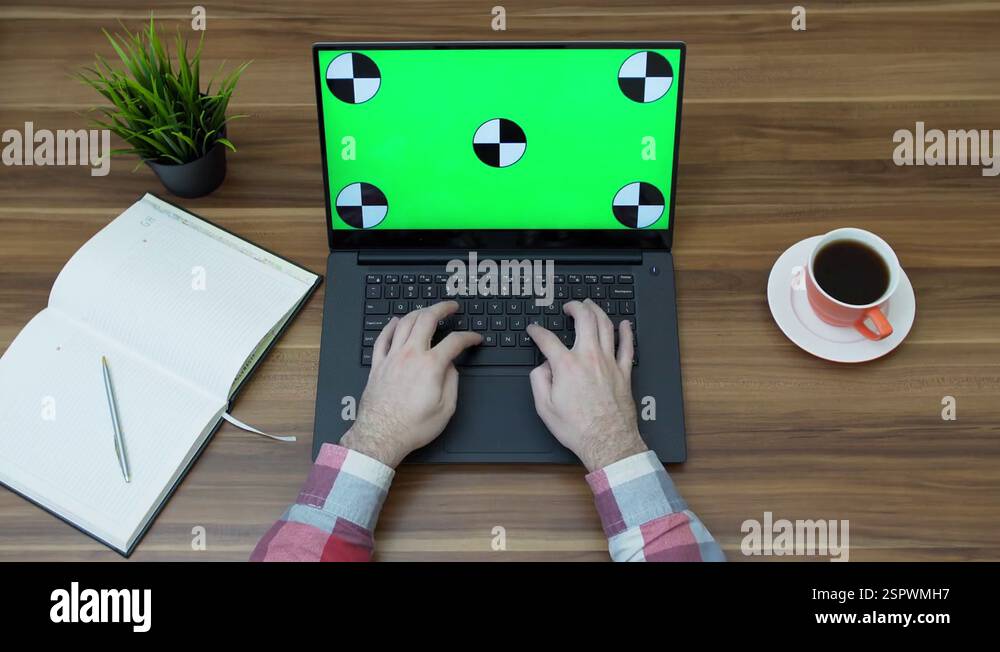 Office table with laptop computer with green screen and male hands ...