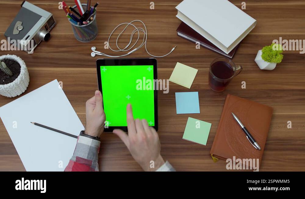The office desk and tablet computer with green screen and male taping ...